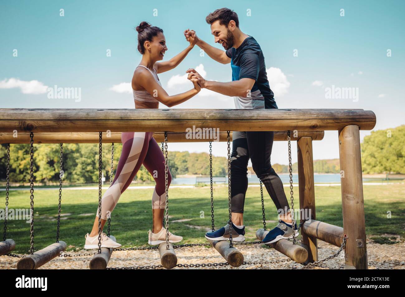 Man and woman playfighting on balance logs on a fitness trail Stock ...