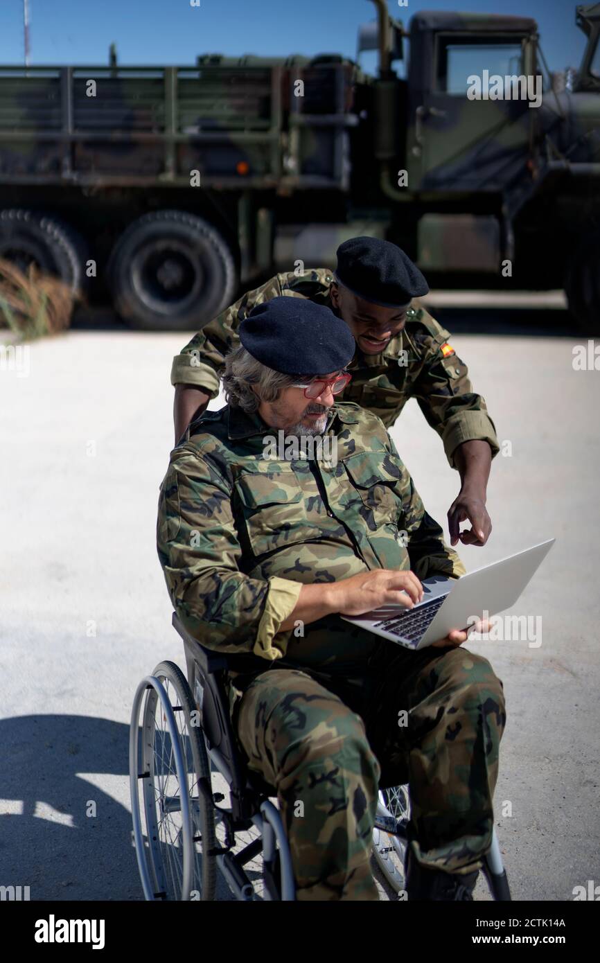 Disabled military officer working on laptop with coworker during sunny ...