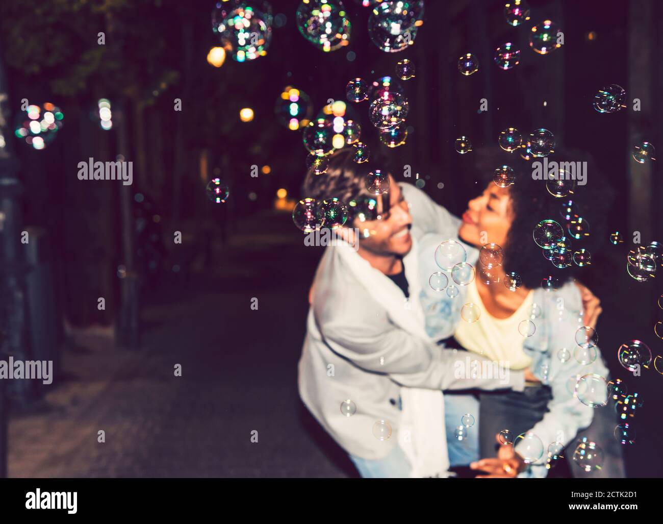 Close-up of bubbles with couple dancing on street in background at ...
