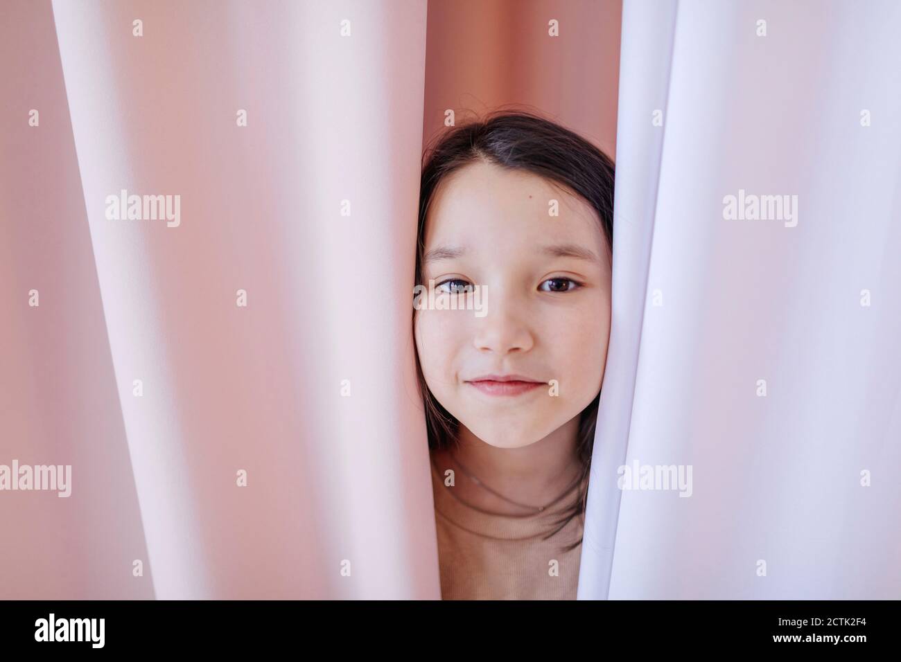 Girl hiding behind curtain at home Stock Photo - Alamy