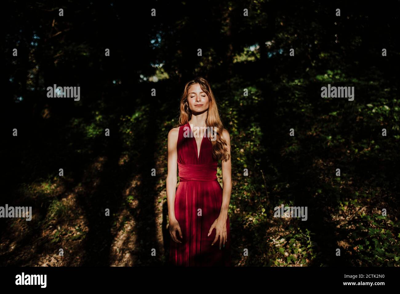 Beautiful woman standing in forest against trees Stock Photo - Alamy