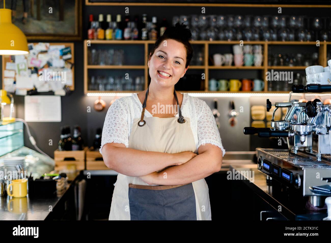 Smiling female barista with arms crossed standing in coffee shop Stock ...
