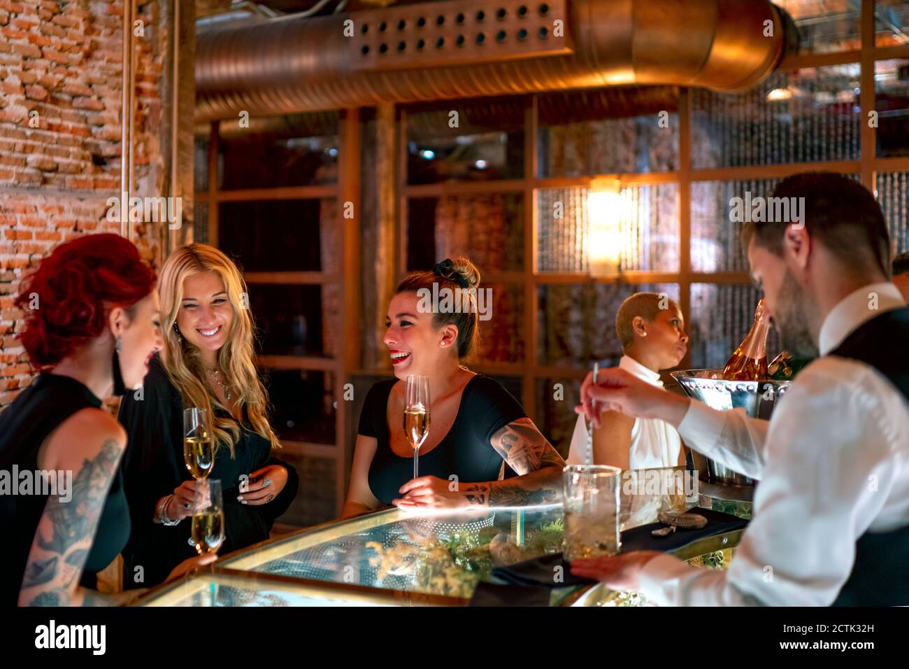Smiling friends talking while sitting at bar counter in pub Stock Photo ...