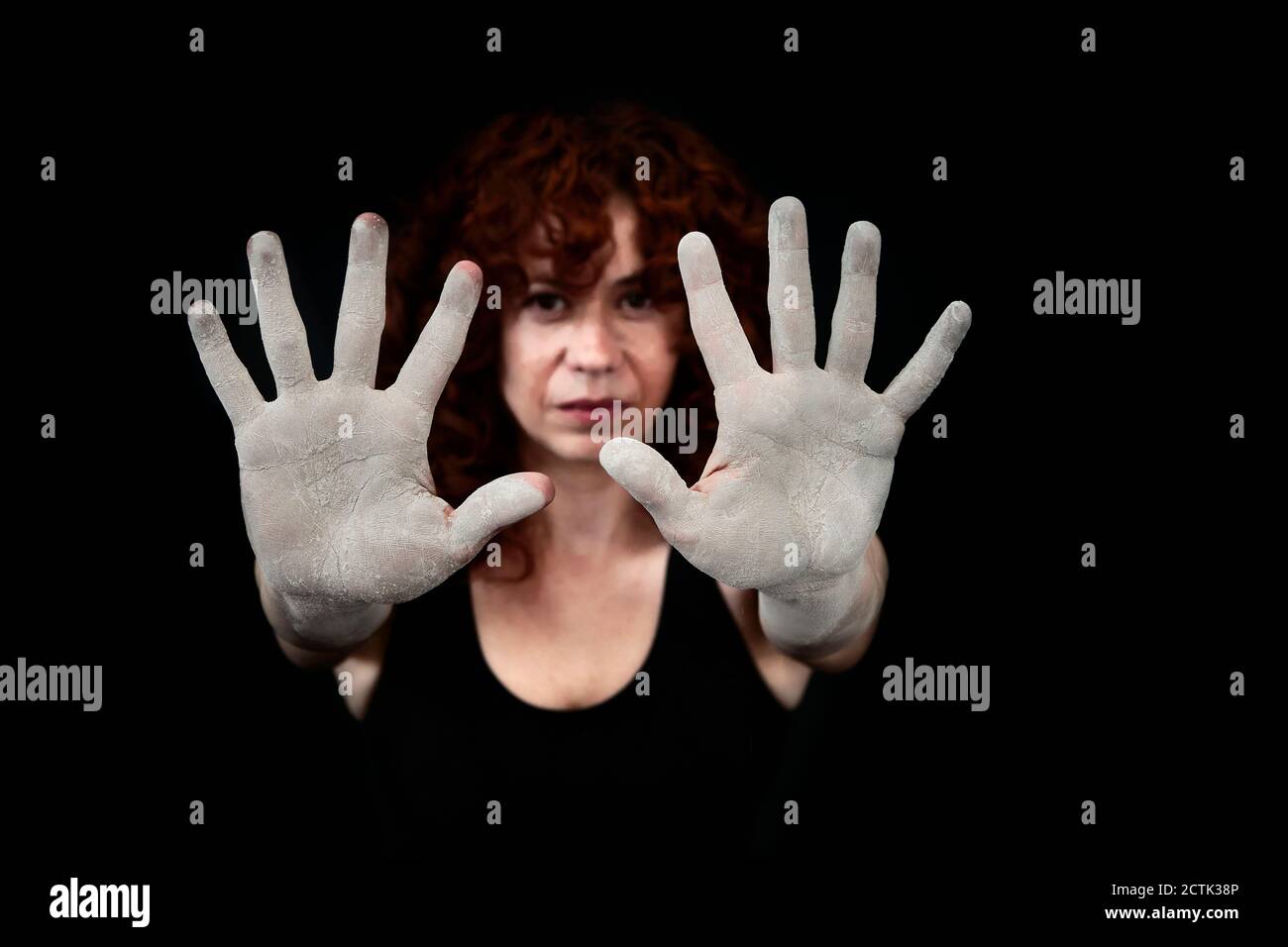 Woman showing hands covered with white dust against black background ...