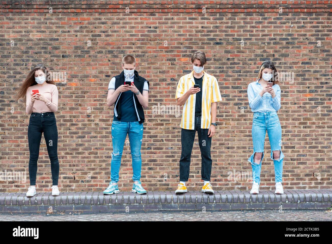 Friends maintaining safe distance while using mobile phones against ...