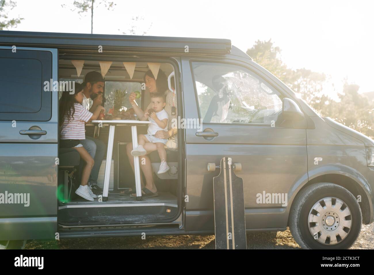 Family eating inside van at park during sunset Stock Photo - Alamy