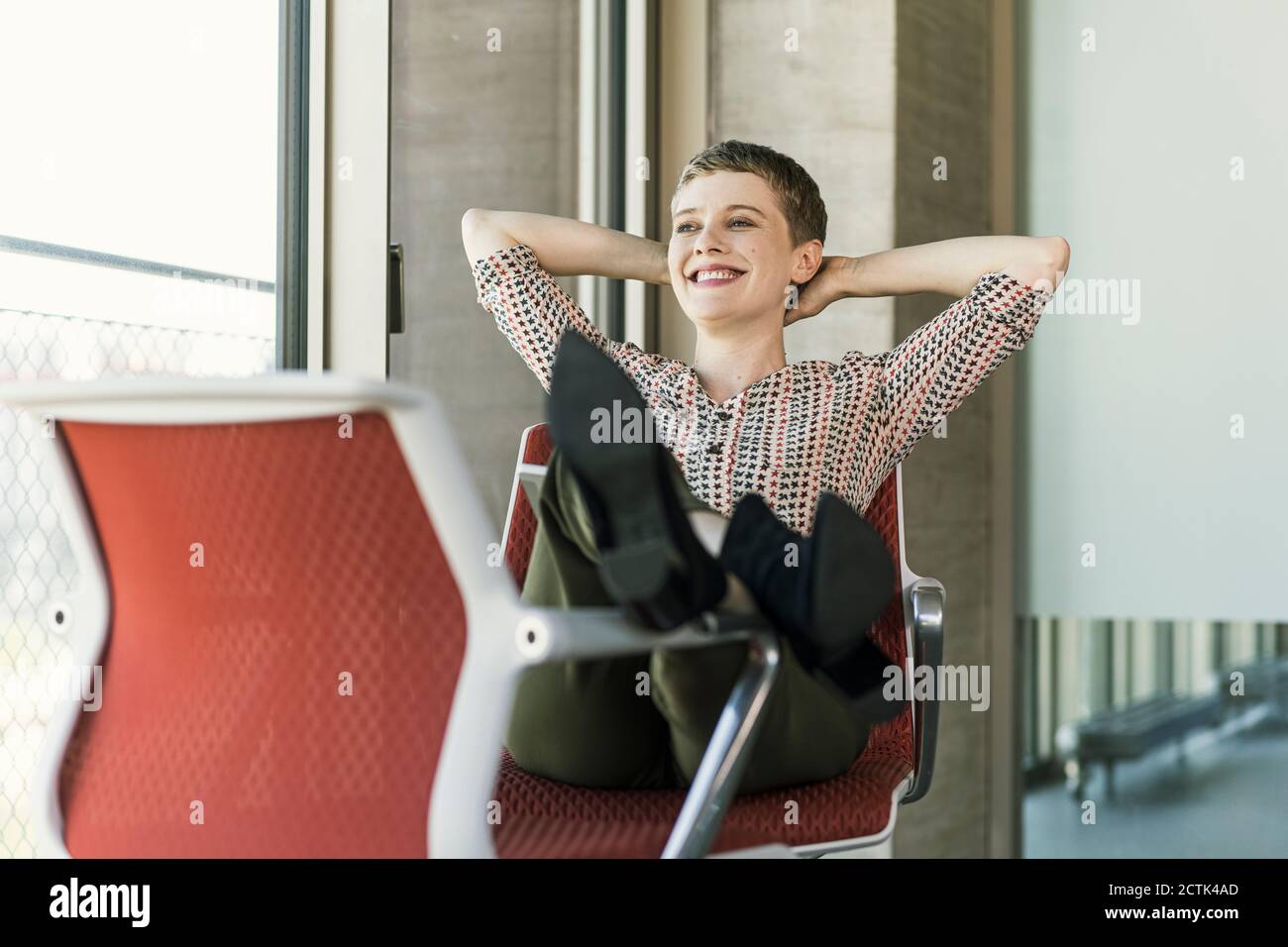 Smiling businesswoman sitting on chair in office having a break Stock ...