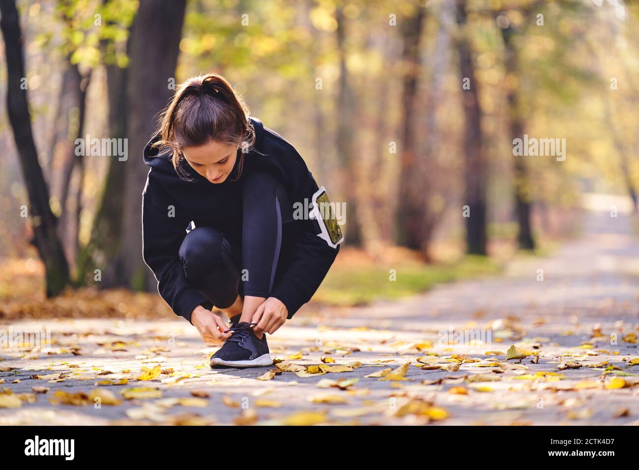 Young woman tying her running shoe Stock Photo - Alamy