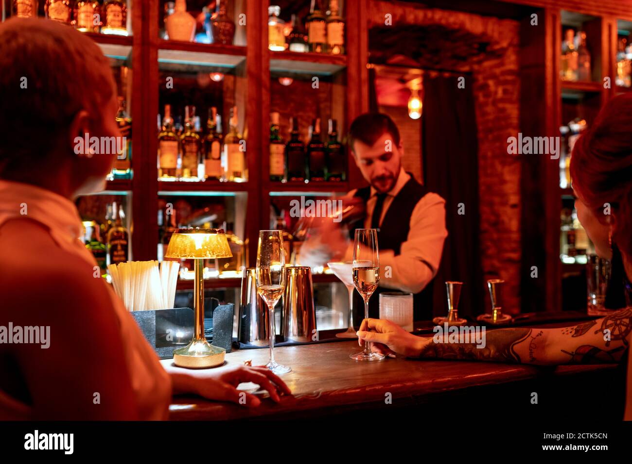 Bartender mixing cocktail while standing at bar counter in pub Stock ...