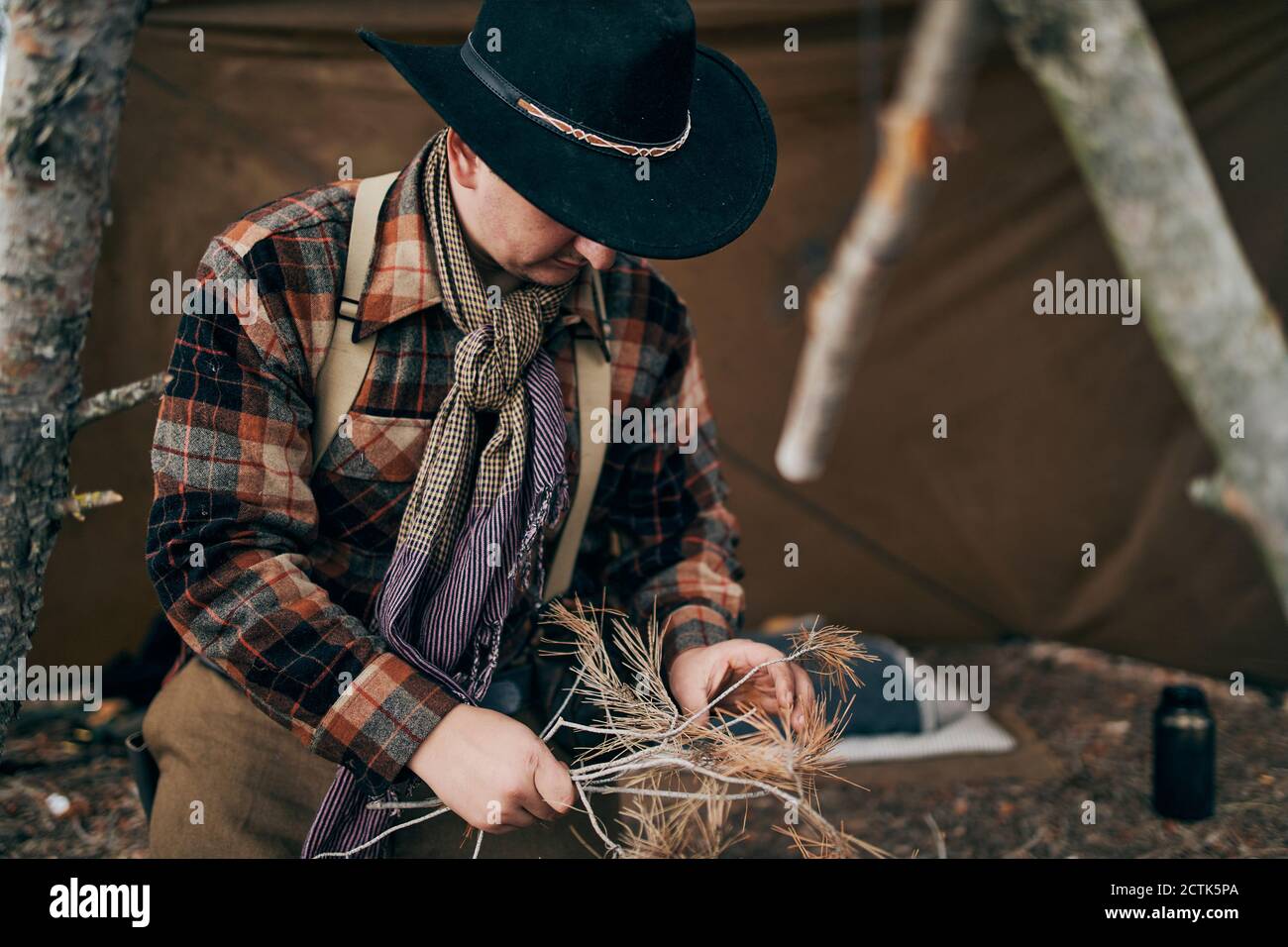 Bushcrafter wearing hat while preparing for campfire Stock Photo - Alamy