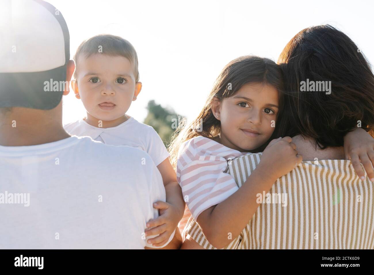 Cute siblings embracing parents at park during sunset Stock Photo - Alamy