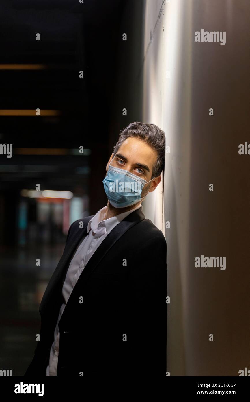 Male professional wearing mask standing by white wall at station Stock ...
