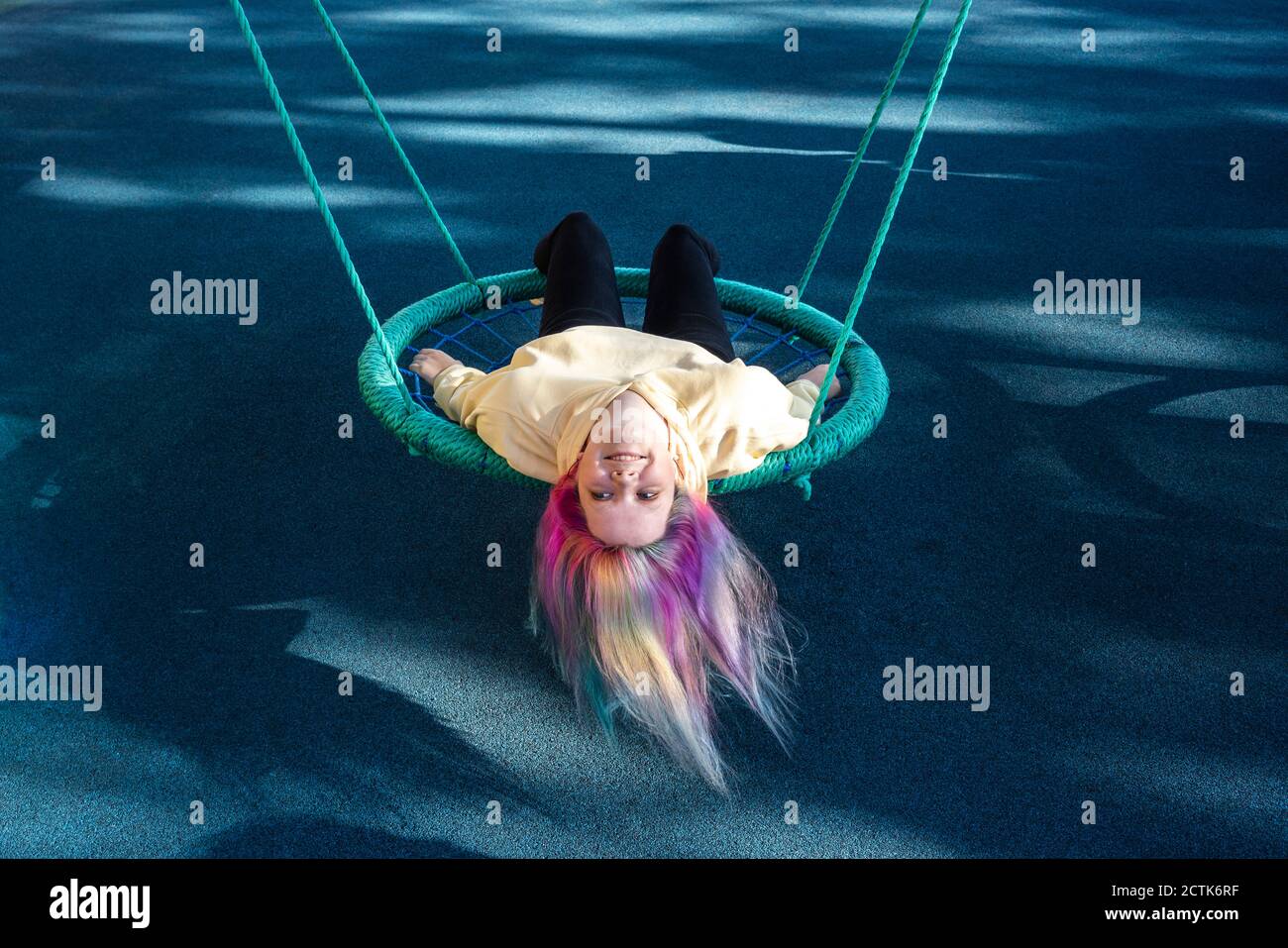 Young woman with dyed hair lying on swing Stock Photo - Alamy