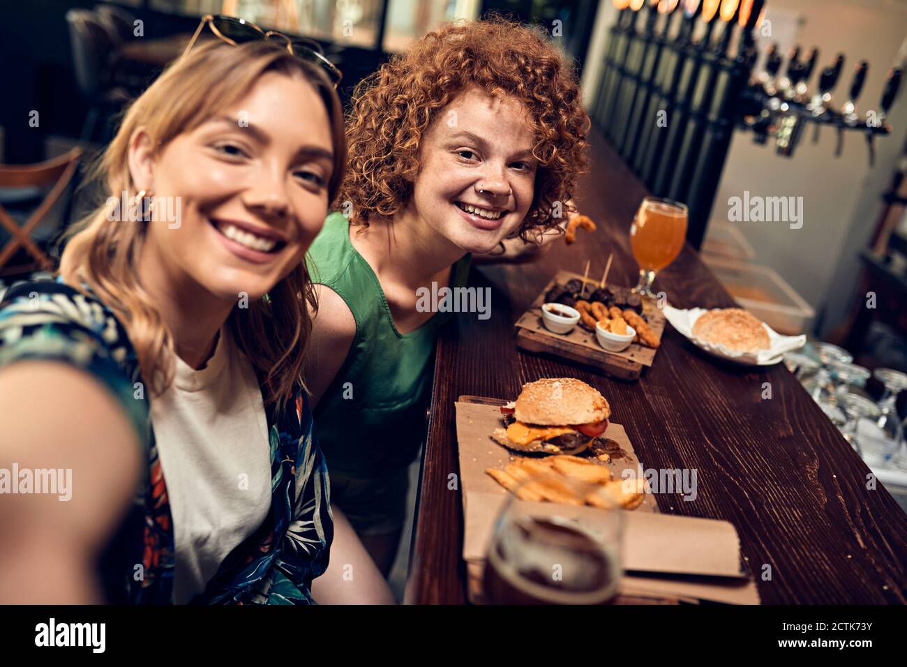 Happy female friends socializing in a pub taking a selfie Stock Photo ...