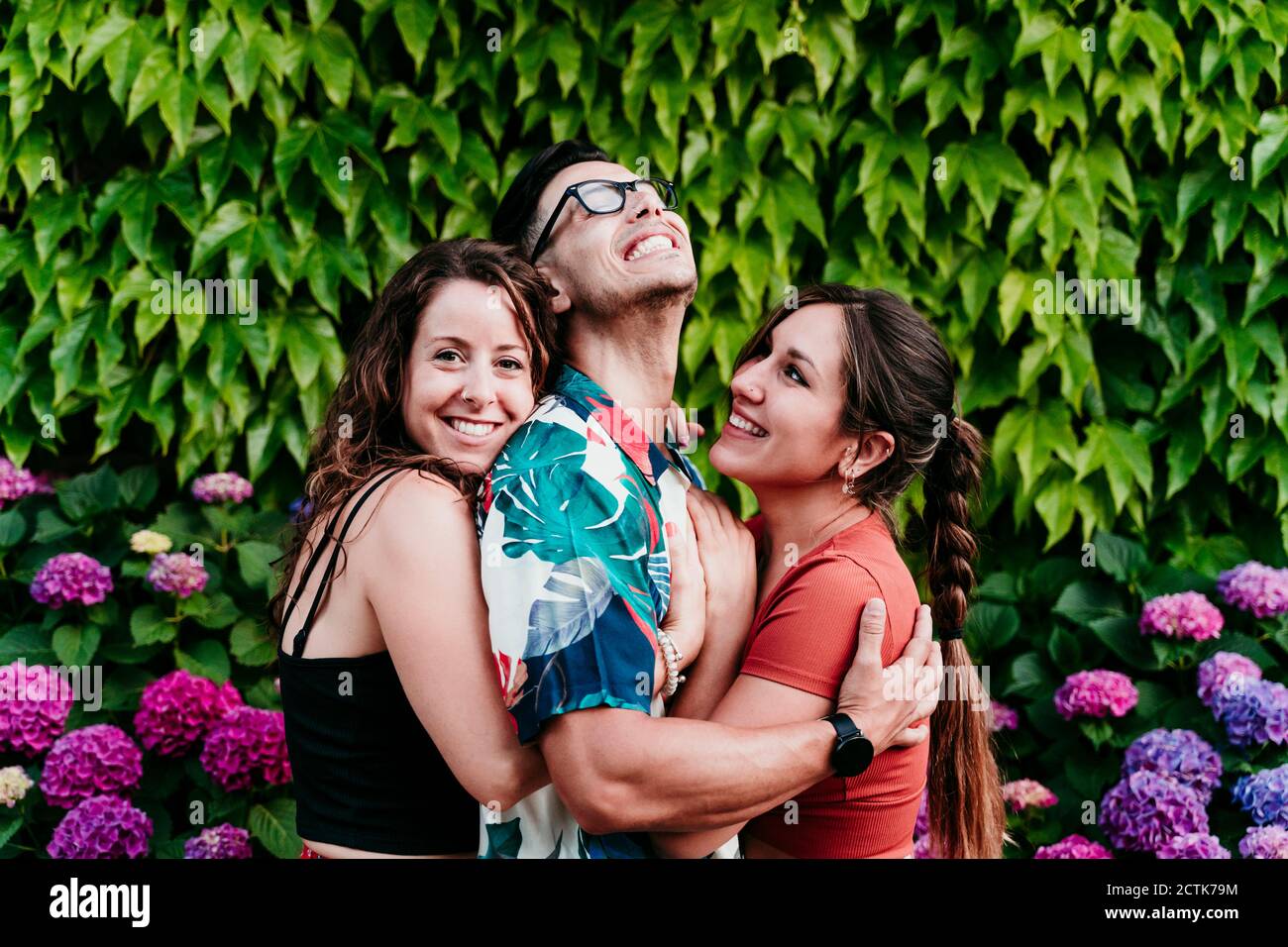 Friends embracing each other against ivy hedge Stock Photo - Alamy