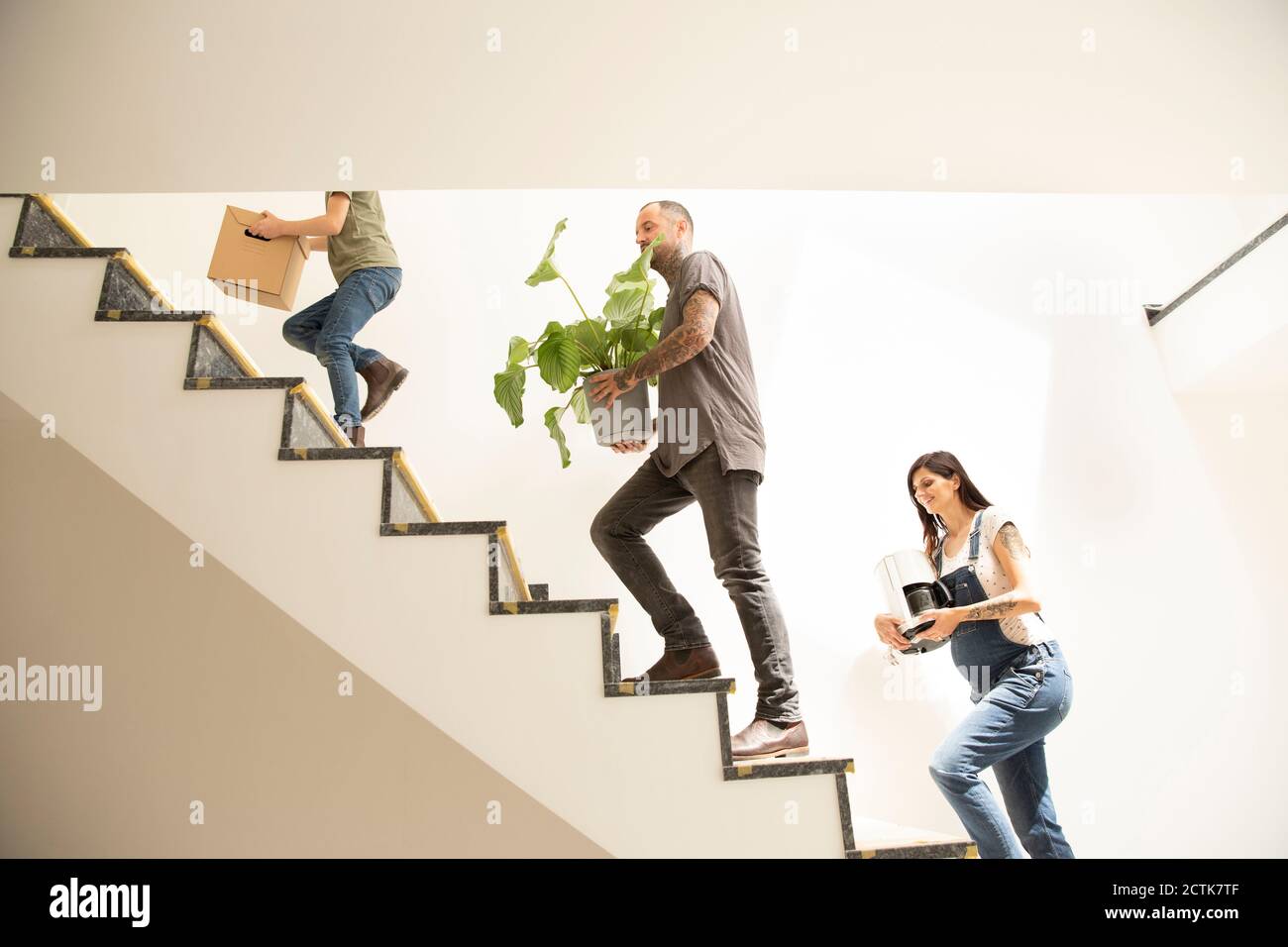 Family carrying various objects while moving up on steps in new ...