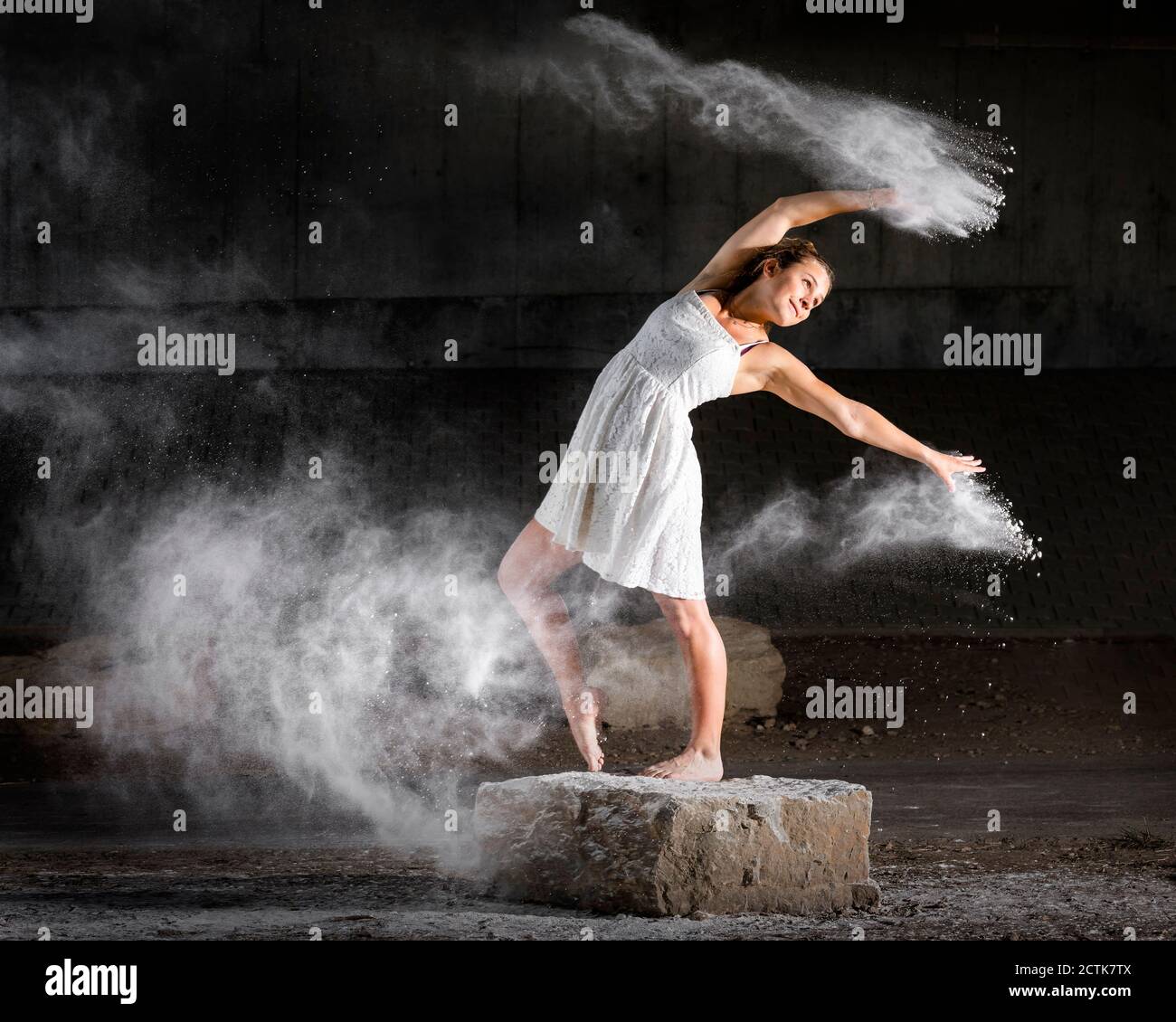 Beautiful woman dancing while splashing flour against wall Stock Photo ...