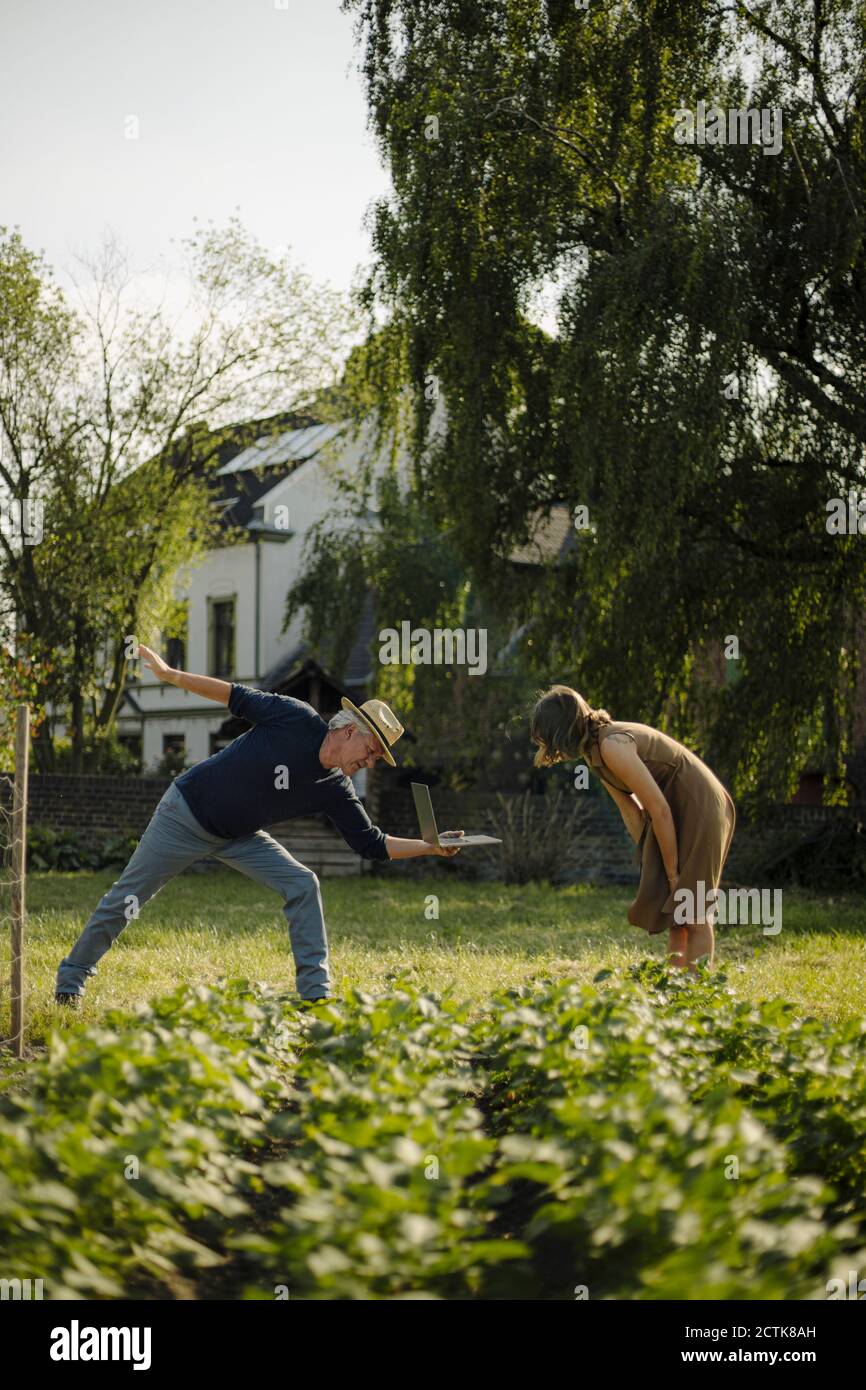 Man giving laptop to woman while standing in backyard Stock Photo - Alamy