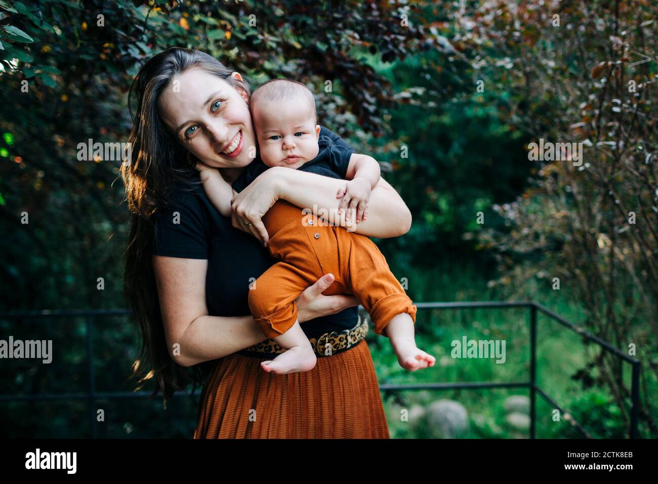 Happy young woman carrying baby boy at park Stock Photo - Alamy