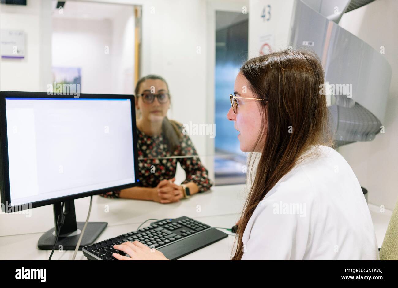 Female pharmacist looking patient's record over computer in hospital ...