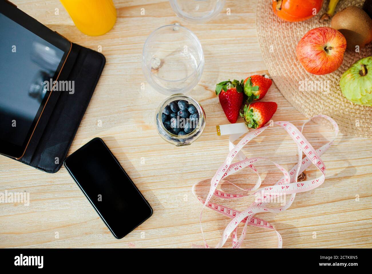 Digital tablet and mobile phone kept with fruit and measurement tape on ...