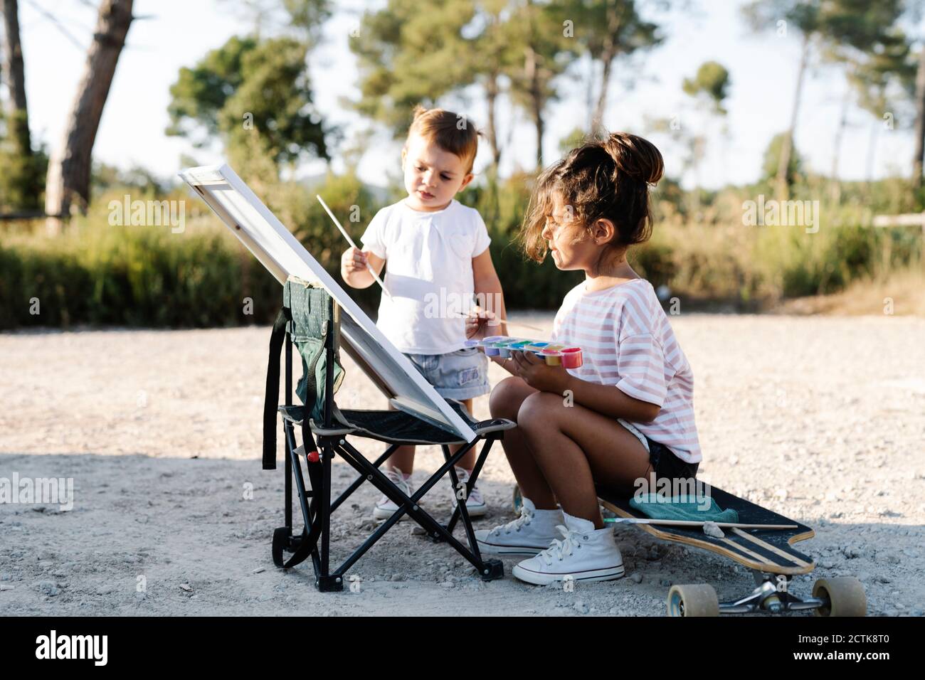 Baby girl painting with sister on canvas at park during sunset Stock ...