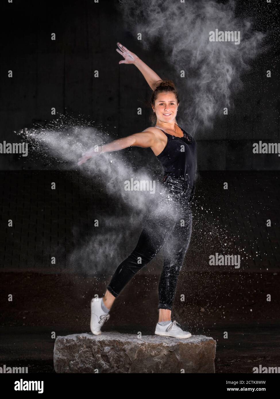 Young woman dancing with flour against wall Stock Photo - Alamy