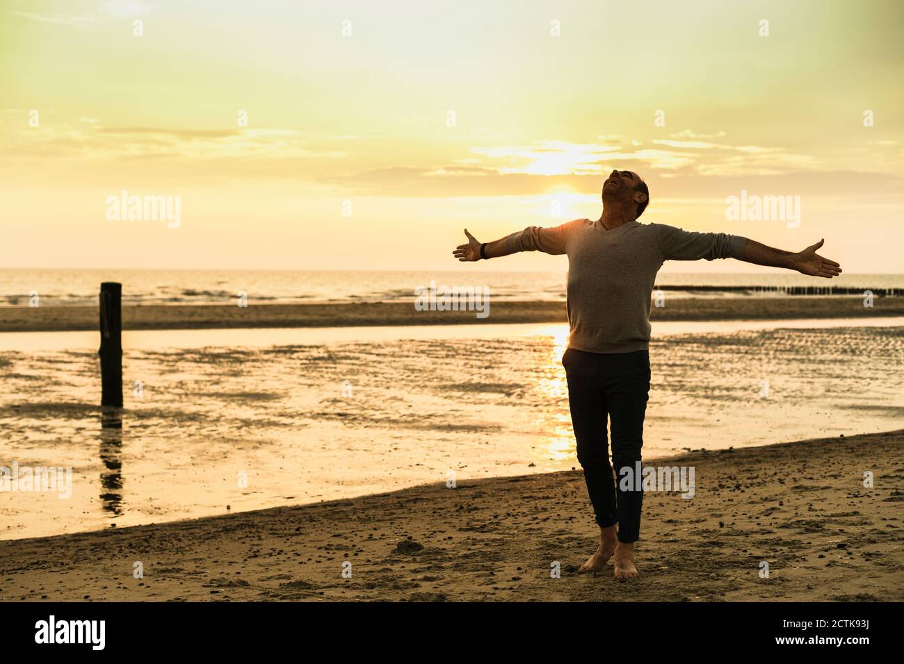Man standing beach sunset outstretched arms hi-res stock photography ...