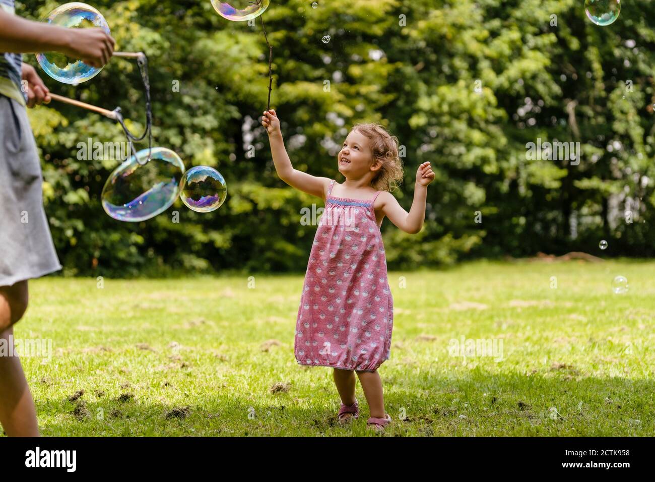 Cute girl exploding bubble with stick by brother at park Stock Photo ...