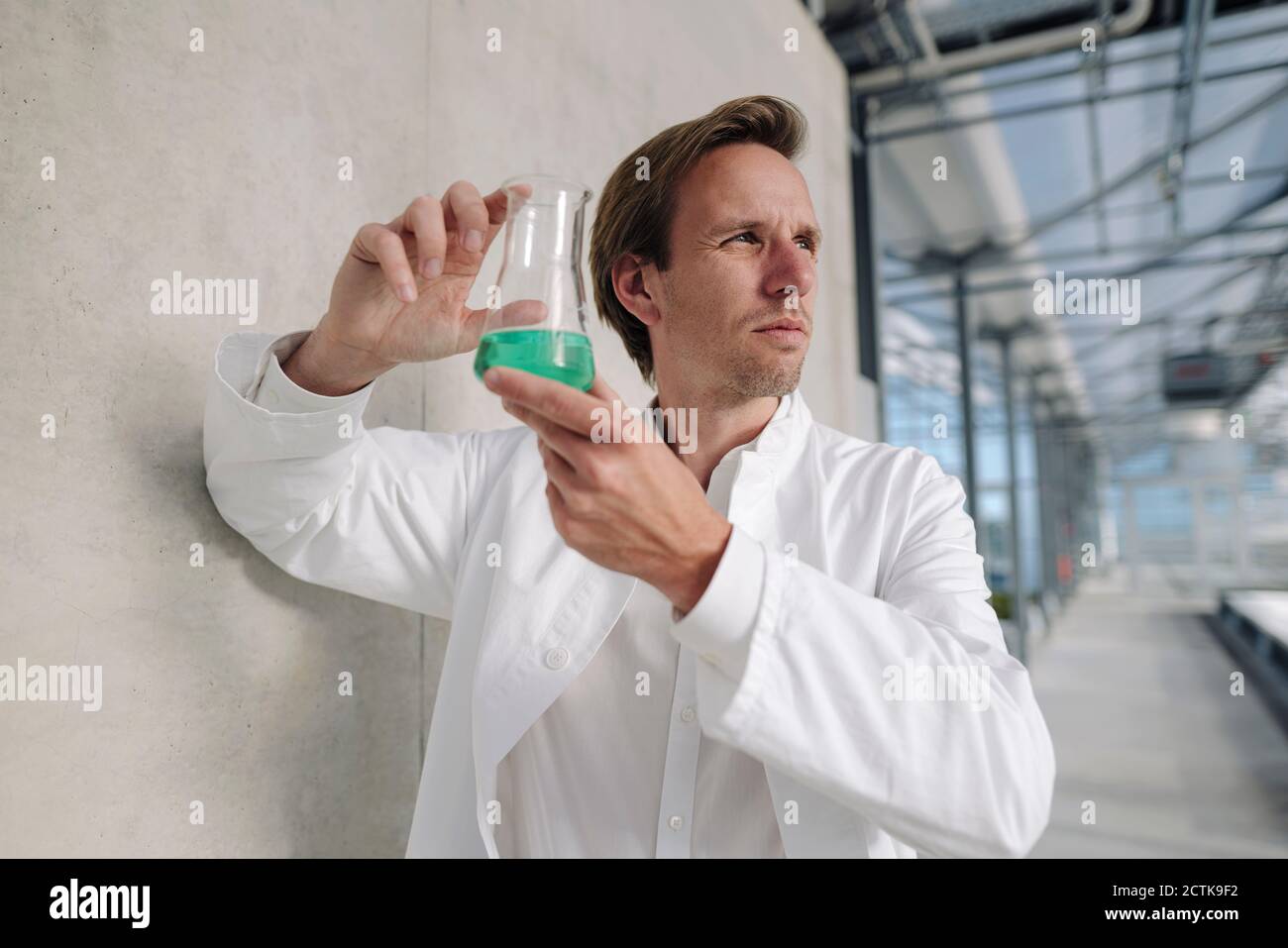 Scientist holding beaker with liquid at a wall Stock Photo - Alamy