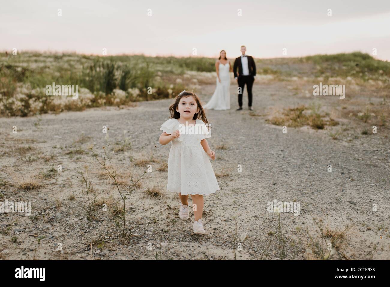Cute daughter running while parents standing against sky Stock Photo ...