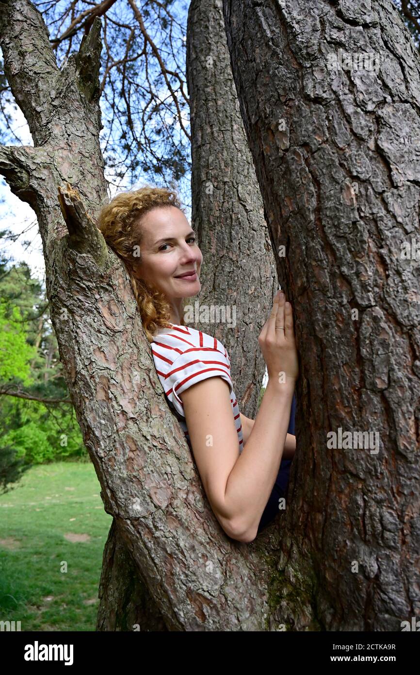 Beautiful woman relaxing while sitting on tree in forest Stock Photo ...