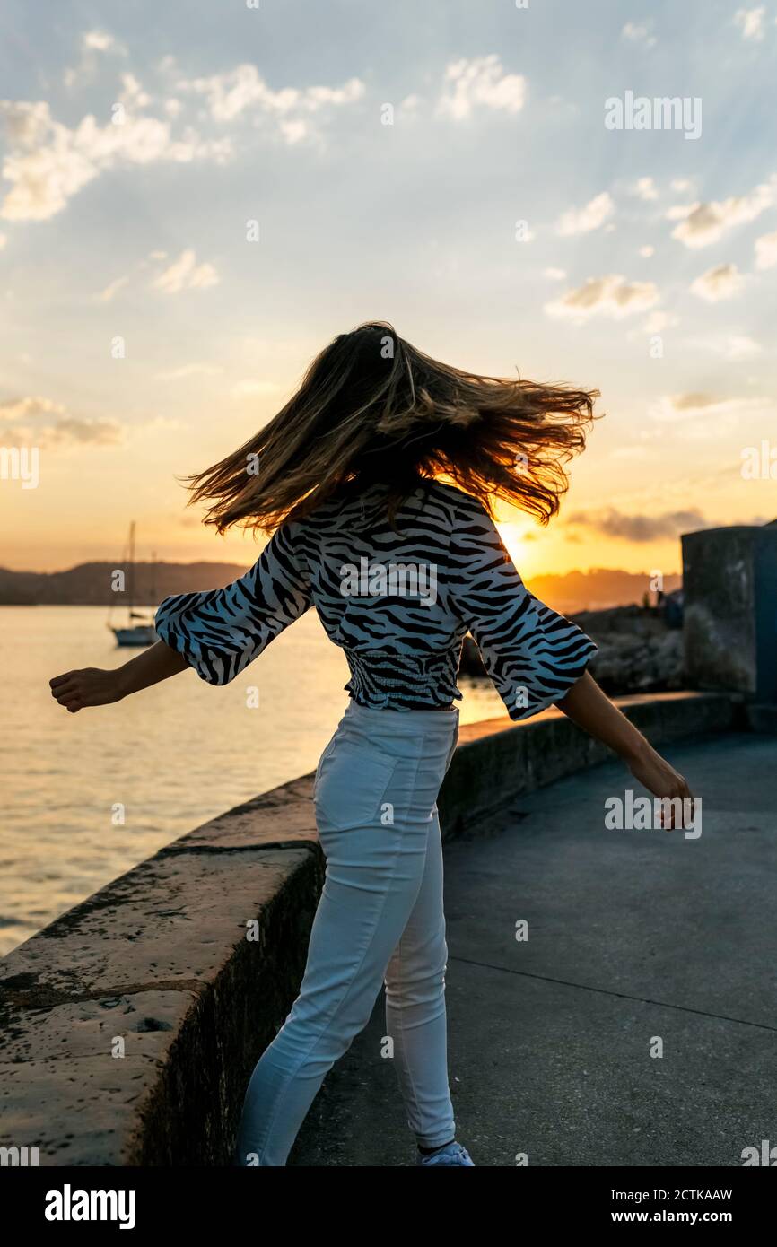 Young woman tossing hair while standing at promenade Stock Photo - Alamy