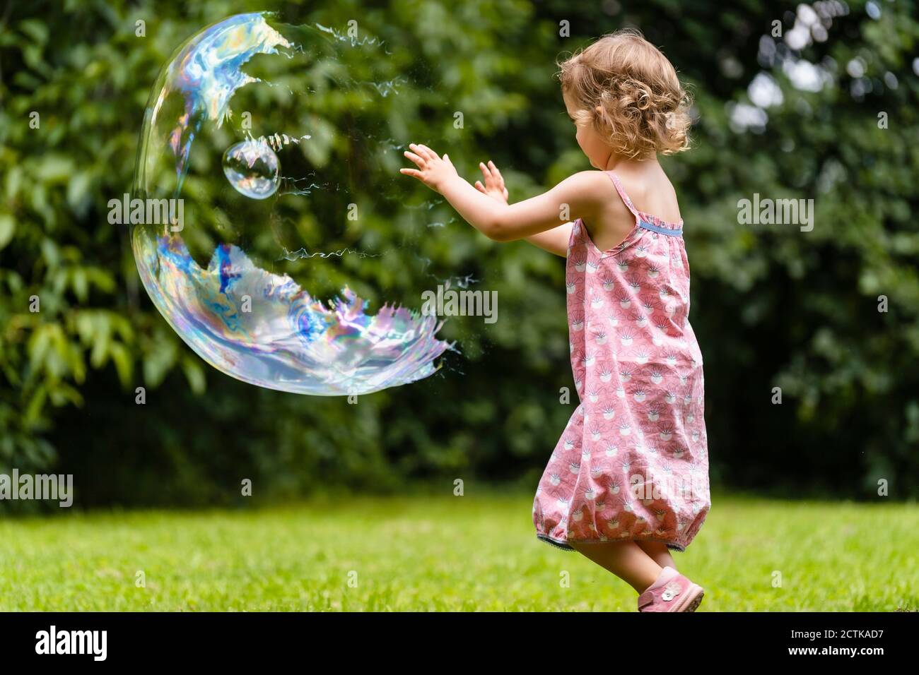 Cute girl exploding bubble at public park Stock Photo - Alamy
