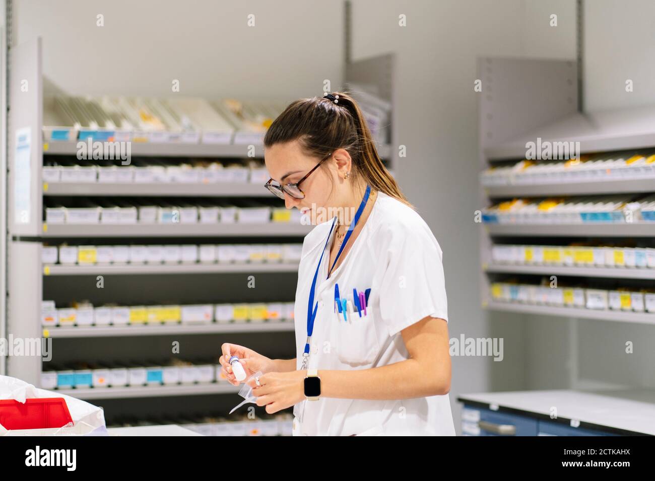 Female worker packing medicines while standing in pharmacy Stock Photo ...