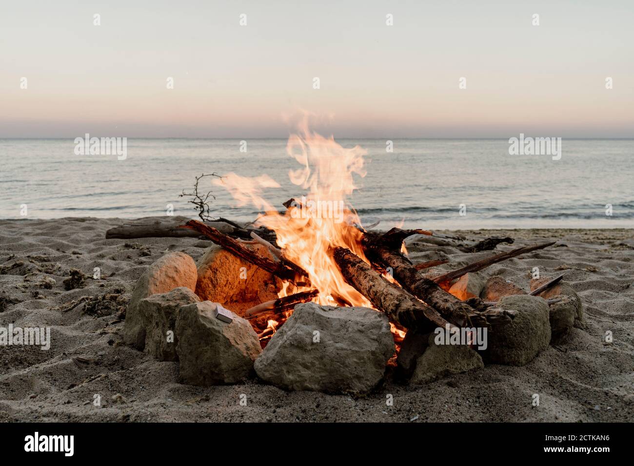 Campfire on empty beach during sunset Stock Photo - Alamy