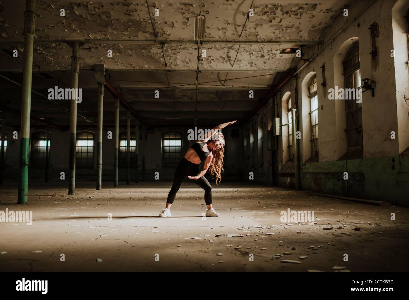 Woman stretching while exercising at abandoned factory Stock Photo - Alamy