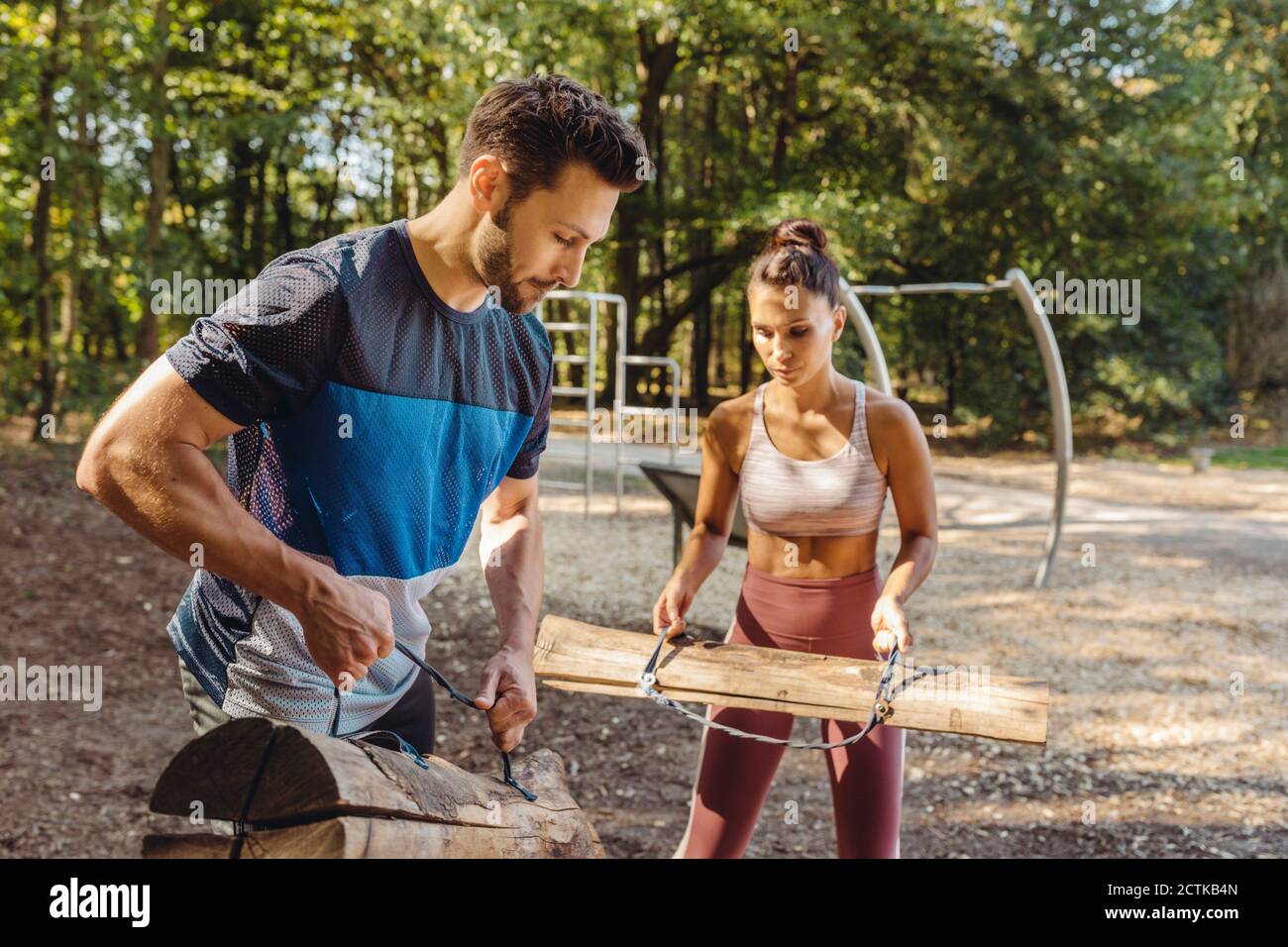 Woman and man lifting up heavy logs on a fitness trail Stock Photo - Alamy