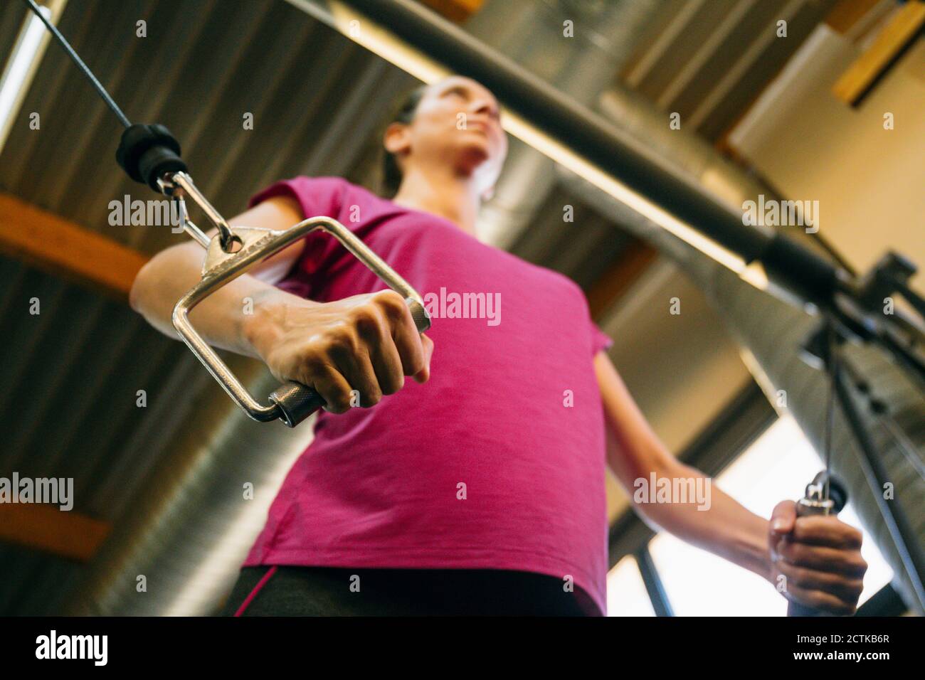 Female athlete pulling exercise equipment while standing in gym Stock ...