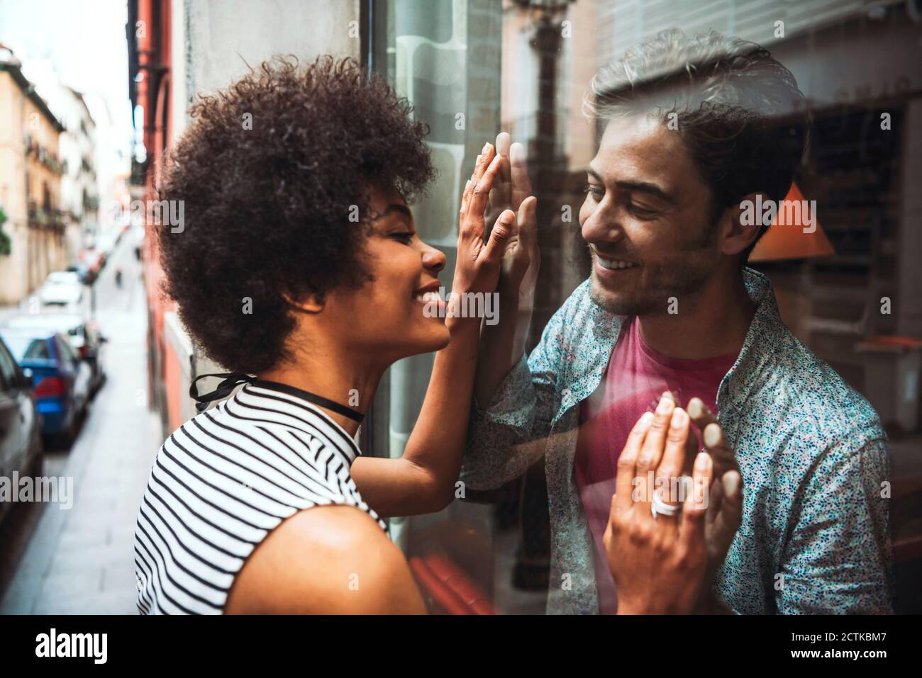 Smiling couple touching glass while looking at each other through ...