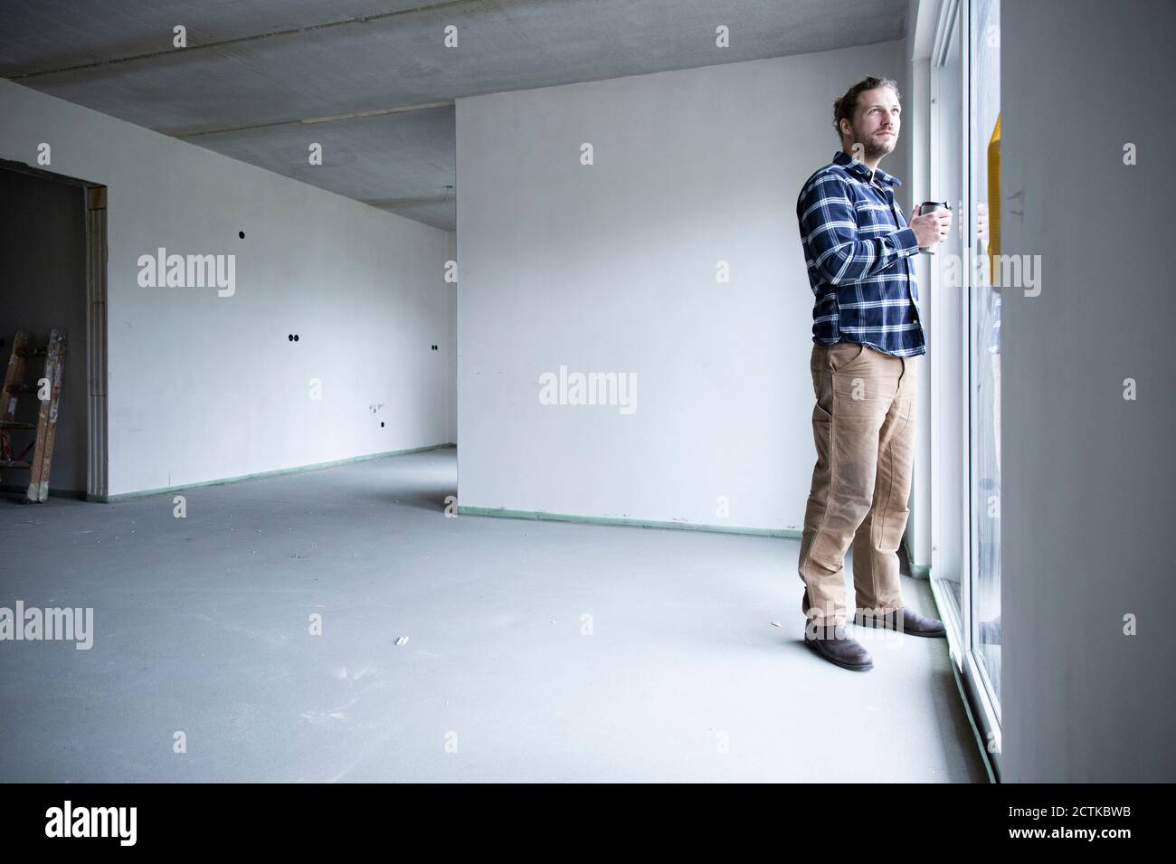 Construction worker looking through window while standing in renovating ...