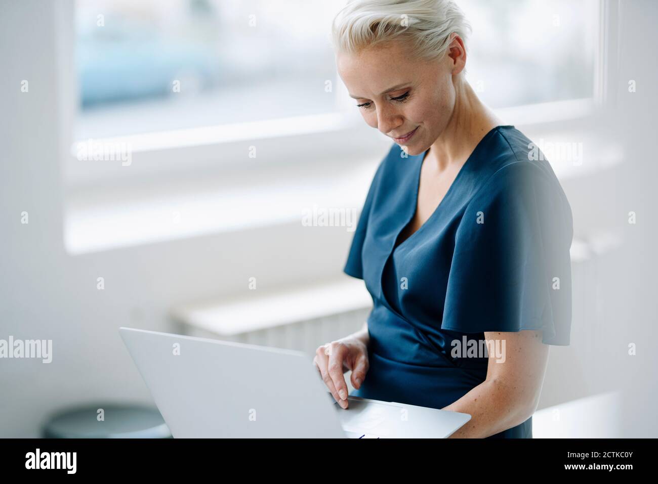 Businesswoman using laptop while sitting in loft office Stock Photo - Alamy