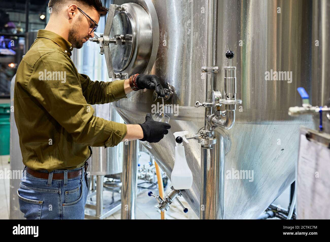 Man working in craft brewery tapping beer from tank Stock Photo - Alamy