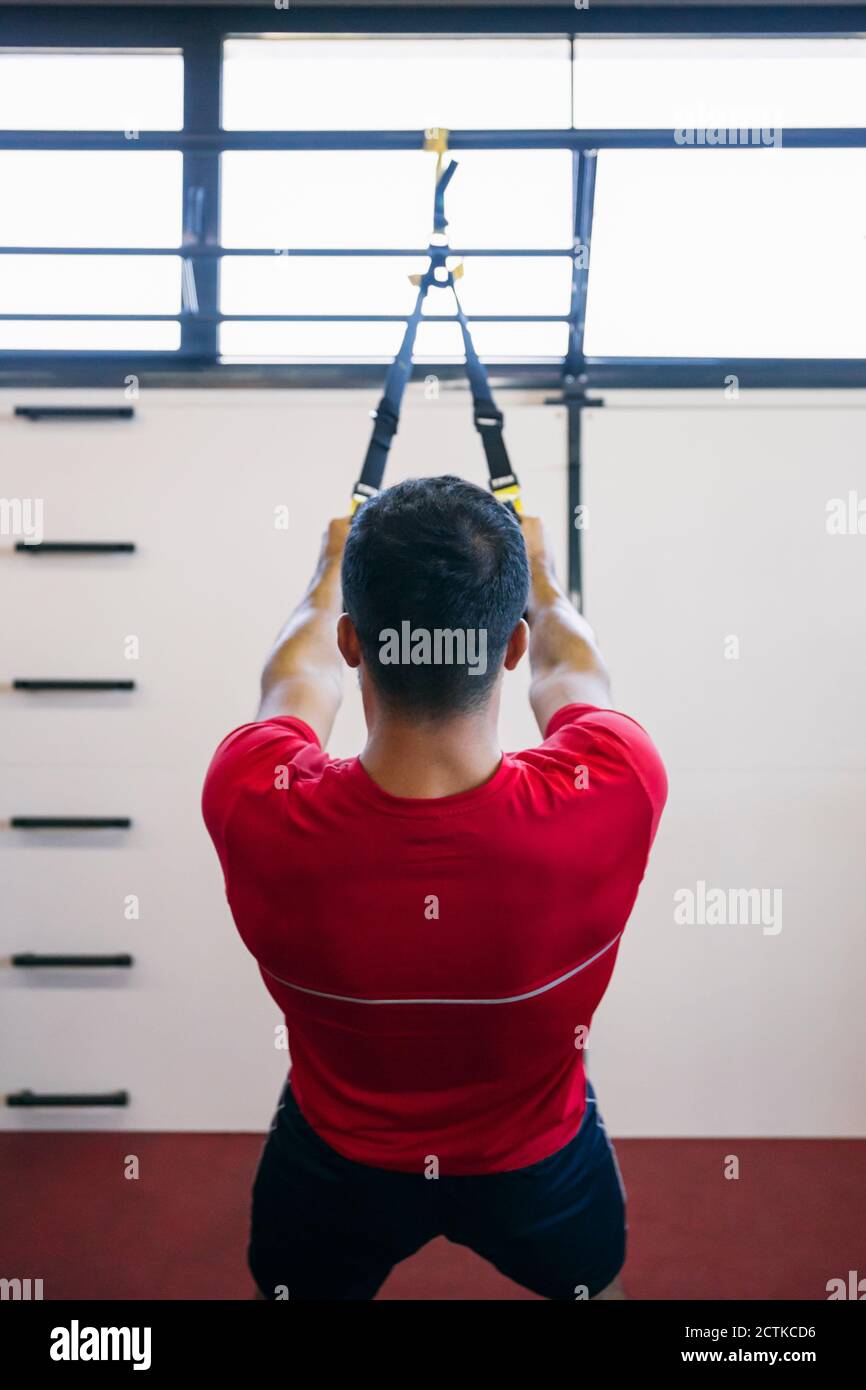 Young man pulling straps while exercising in gym Stock Photo - Alamy