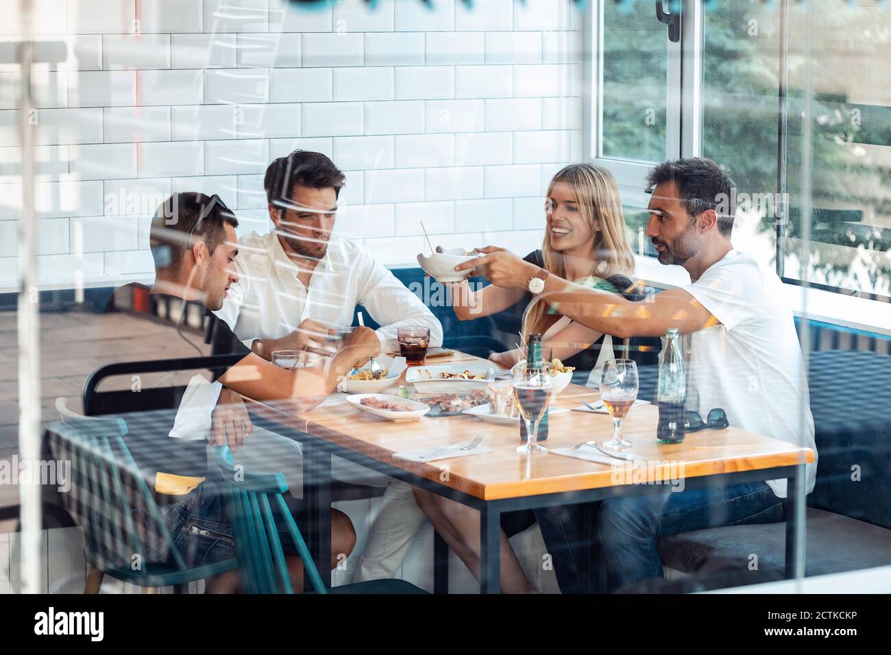 Friends enjoying meal at restaurant seen through window Stock Photo - Alamy
