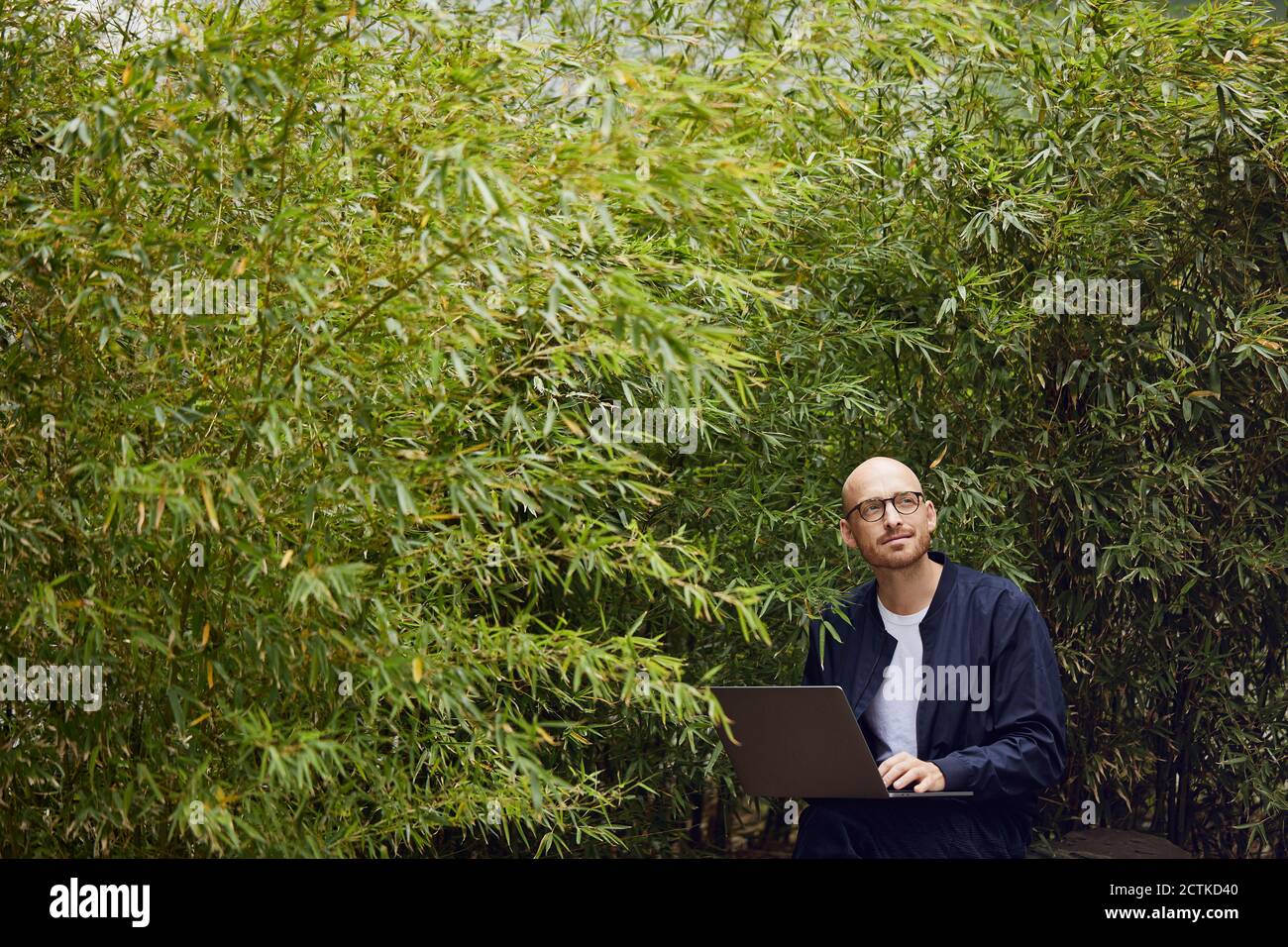 Contemplating man sitting while working on laptop in public park Stock ...