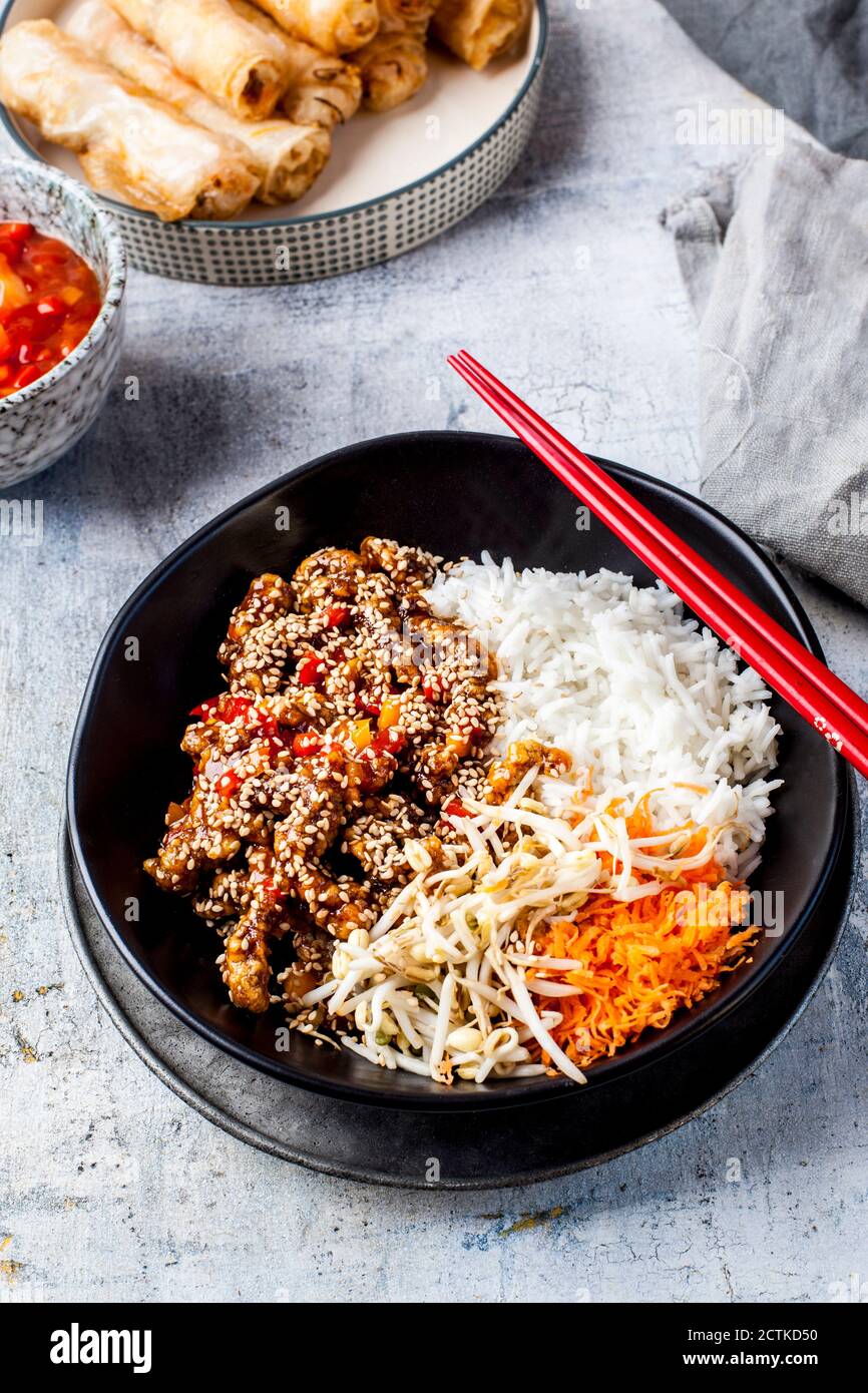 Bowl of fried sesame beef with salad and rice Stock Photo - Alamy