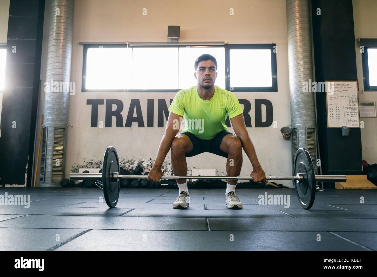 Serious male athlete lifting deadlift while standing in gym Stock Photo ...