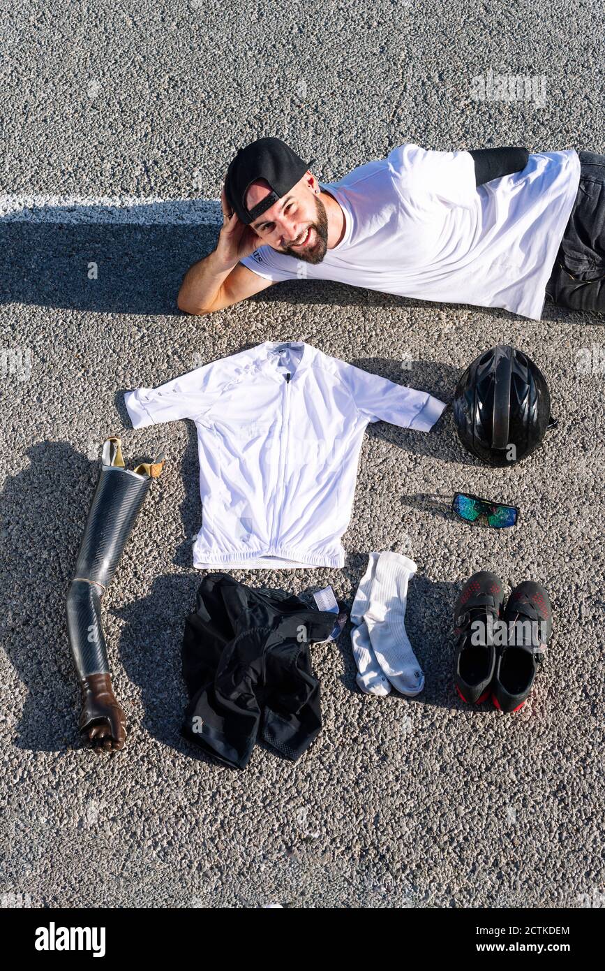 Smiling male amputee athlete with various objects lying on road Stock ...