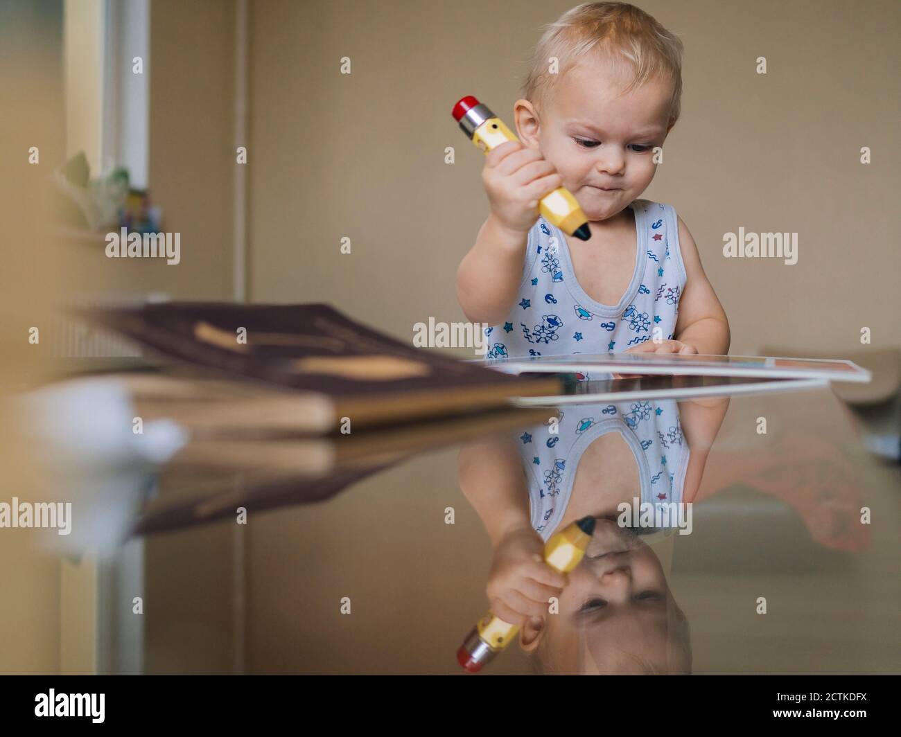Cute blond baby boy holding pencil with reflection at home Stock Photo ...